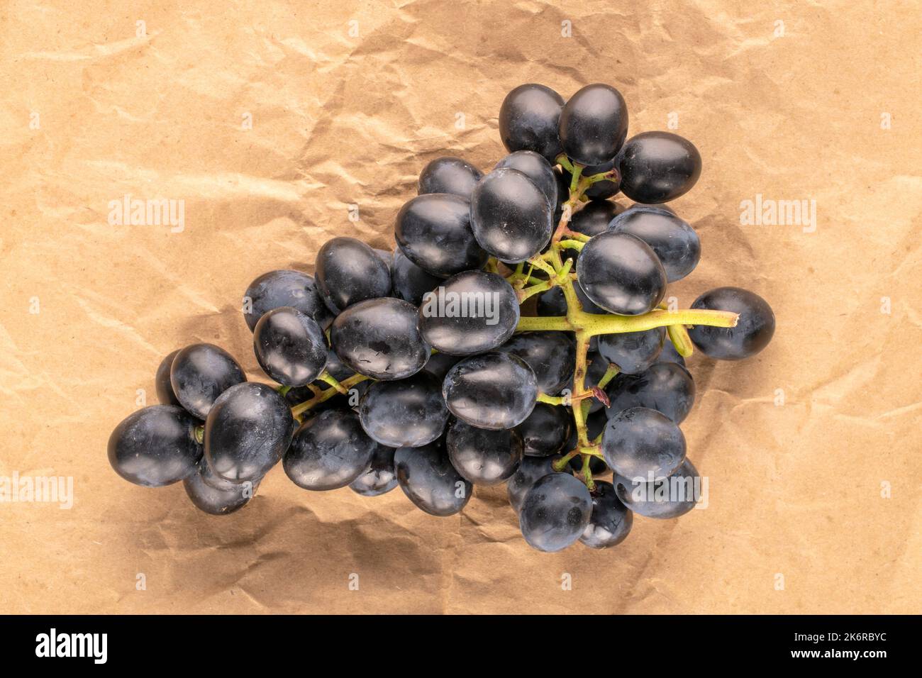 One sprig of sweet black grapes on kraft paper, macro, top view Stock ...
