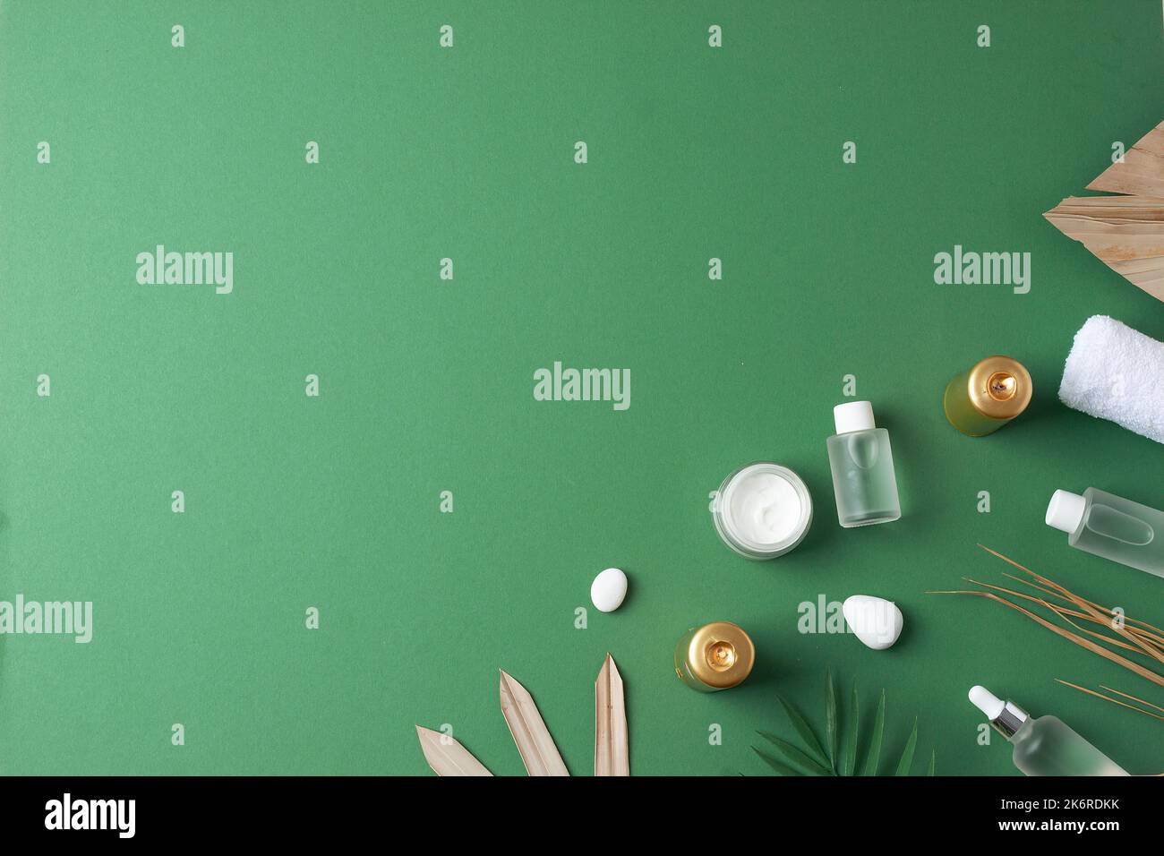 Spa treatment with cosmetic bottle, candles and palm leaf on green ...
