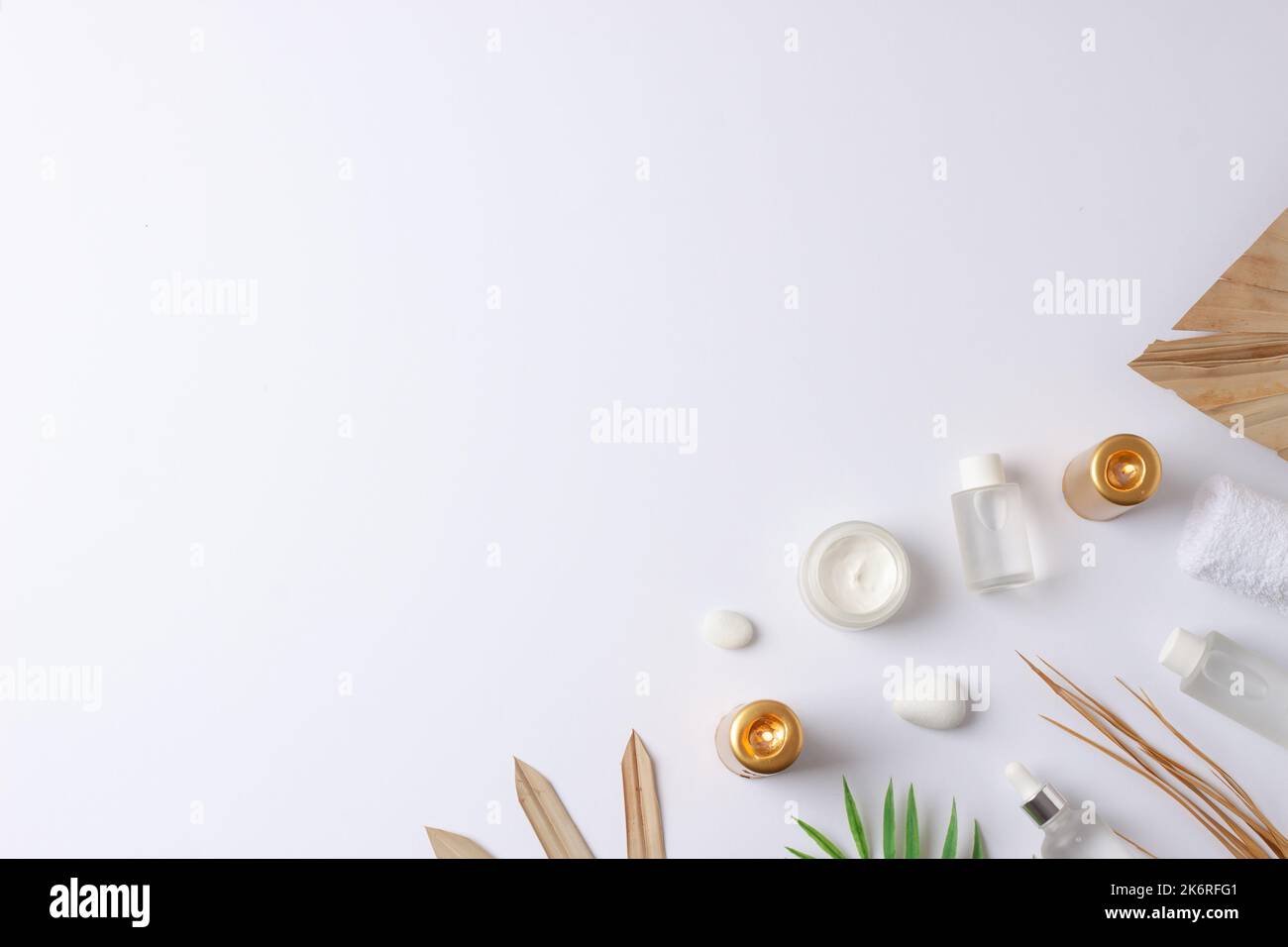 Spa treatment with cosmetic bottle, candles and palm leaf on white ...