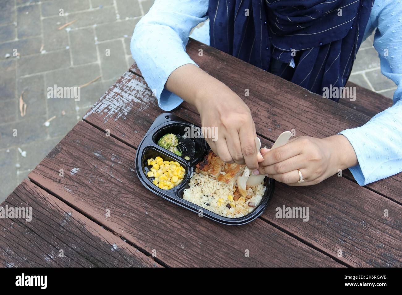 women eating chicken rice in a take away packet in park bench Stock ...