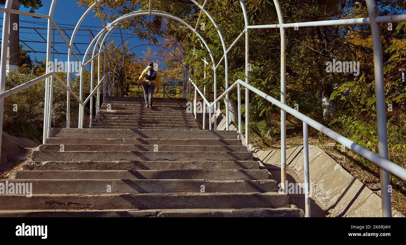 Autumn composition. A woman climbs the stairs to meet the blue sky and ...