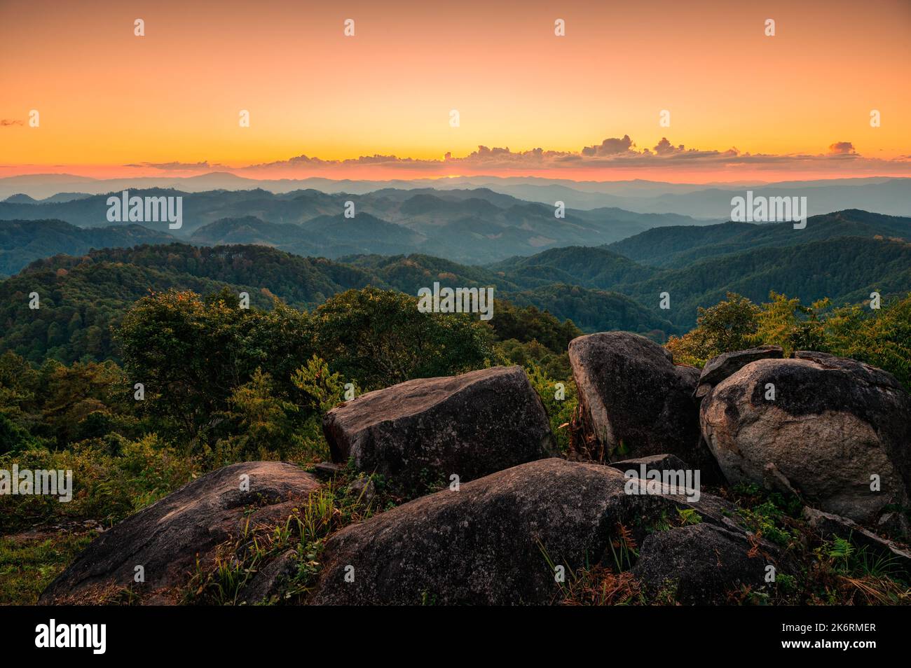 Colorful sunset over mountain range in tropical rainforest and rocks at ...
