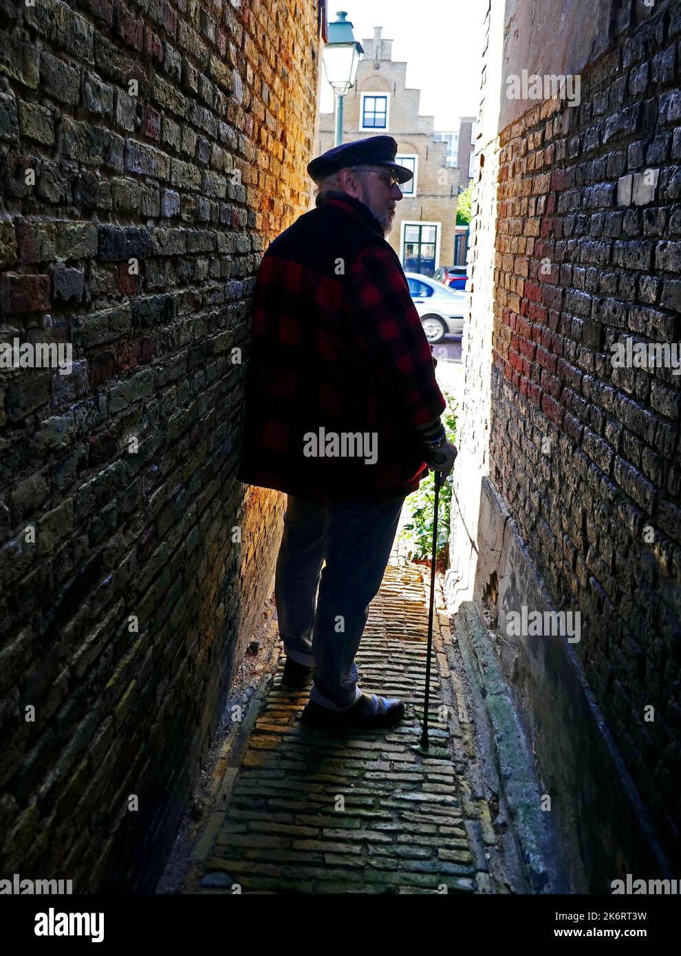 Man with broad shoulders turning at the end of an extreme narrow alley ...