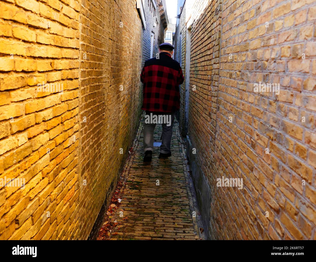Man with broad shoulders walking down an an extreme narrow alley in ...
