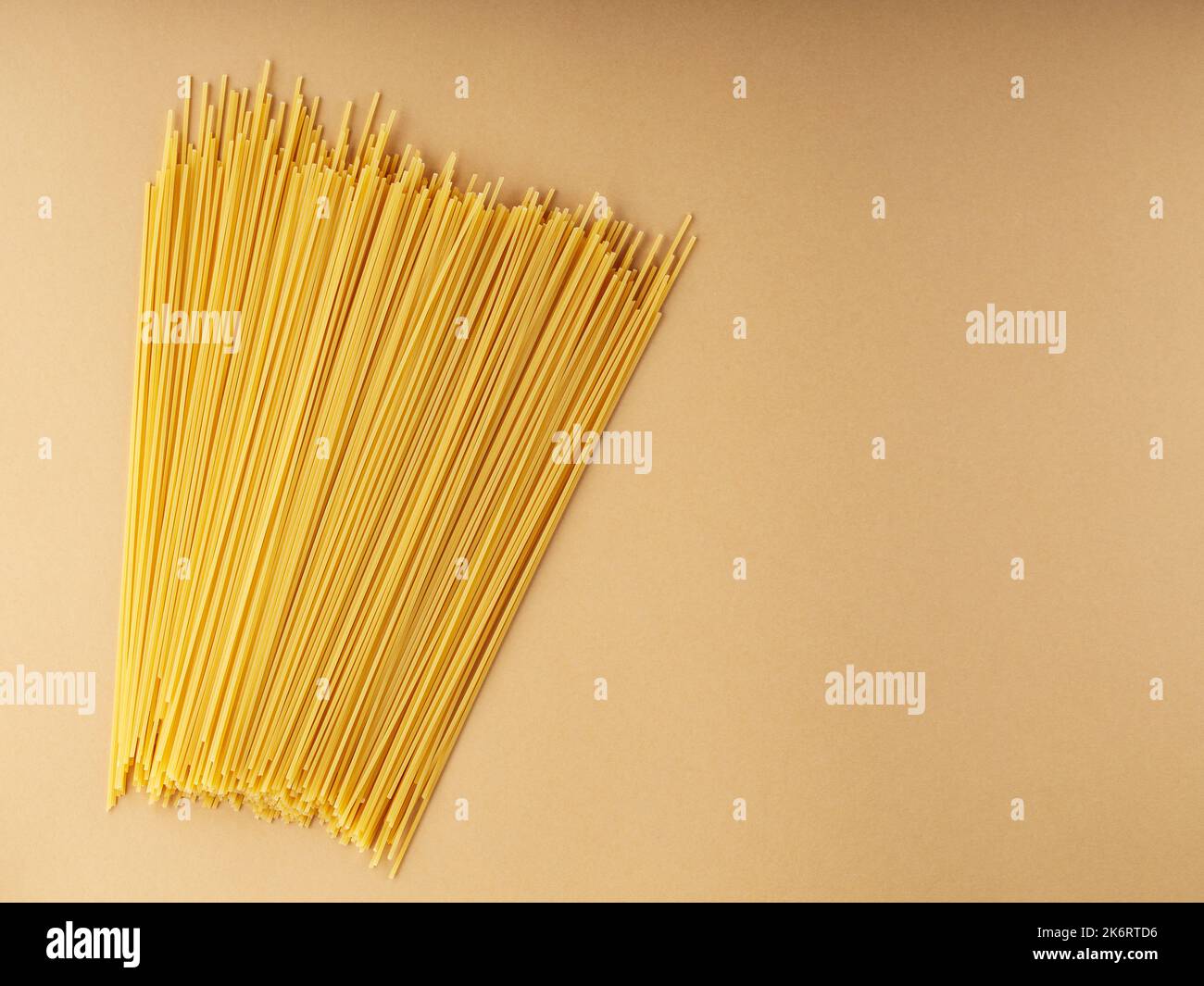 Raw spaghetti pasta on a beige background. Scattered yellow long ...