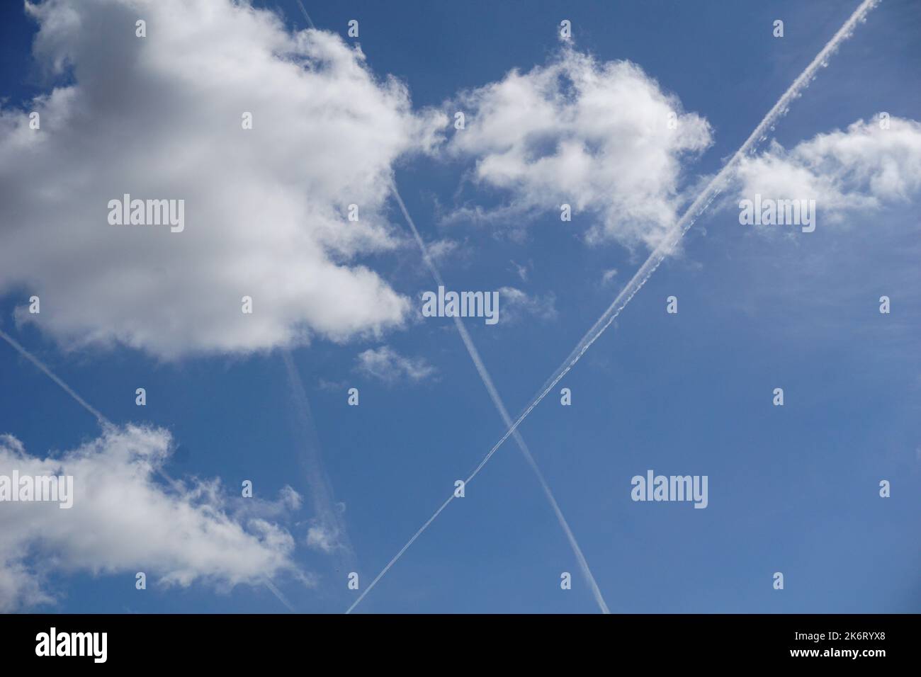 Jet trail patterns in a blue sky with clouds Stock Photo - Alamy