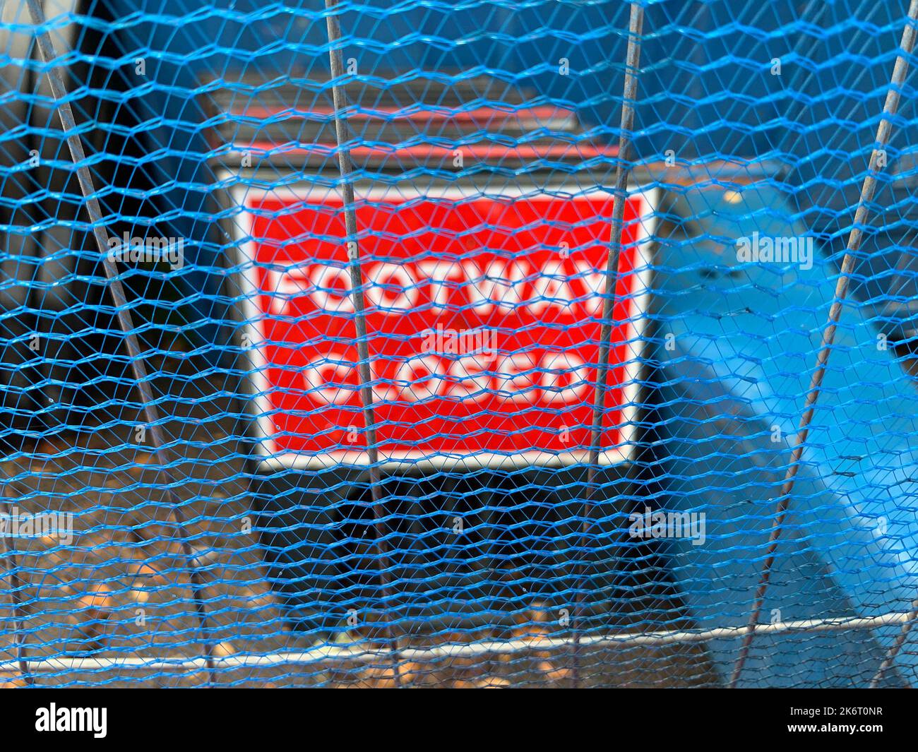 Close up of a blue net with a blurred traffic sign footway closed ...