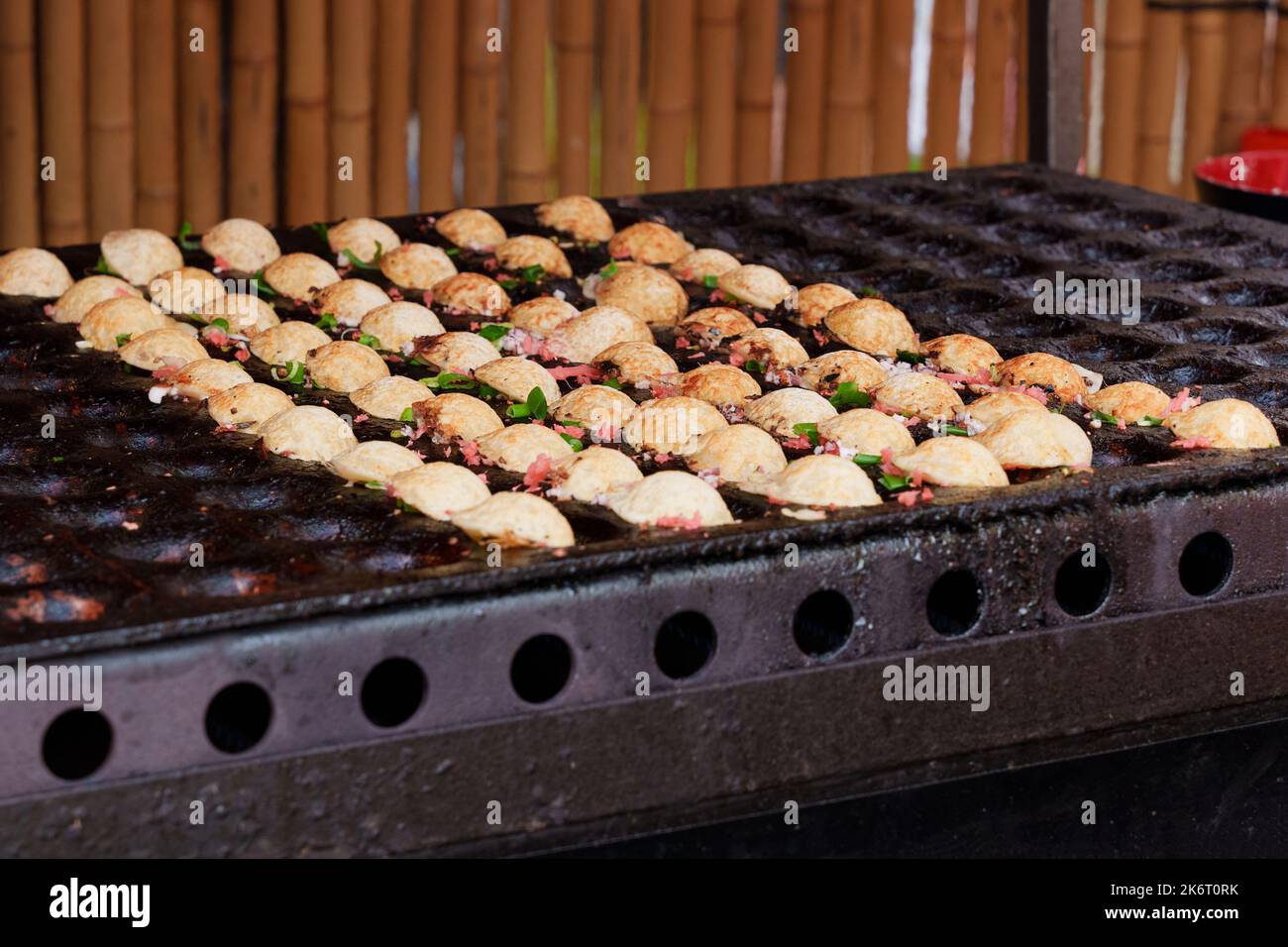 Japanese street food takoyaki at special grill pan. Process of cooking ...
