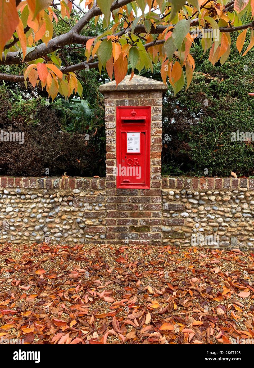 Red UK post office collection box built into a brick wall seen in ...