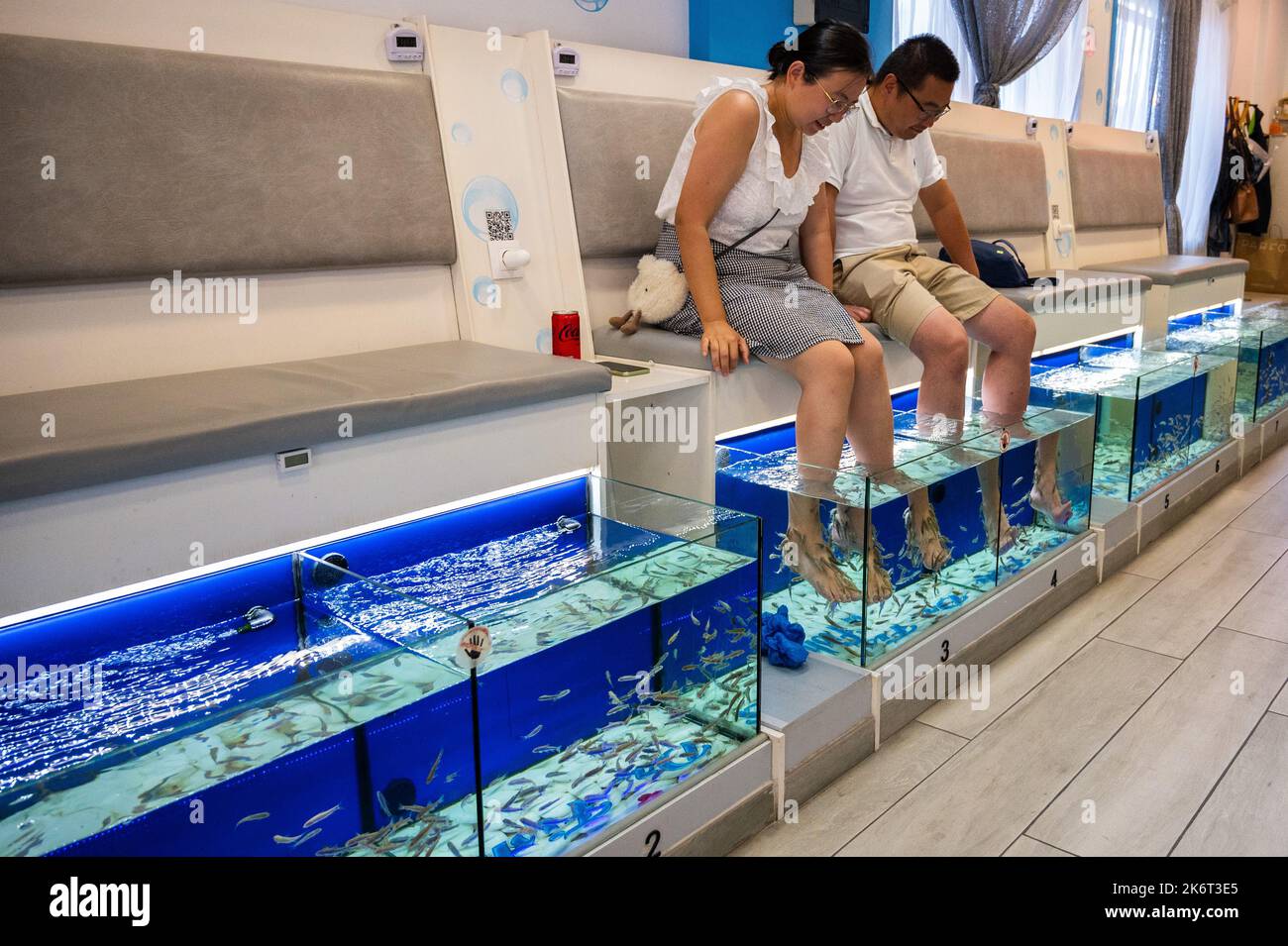 A couple of Asian tourists enjoying a fish pedicure, also known as a ...