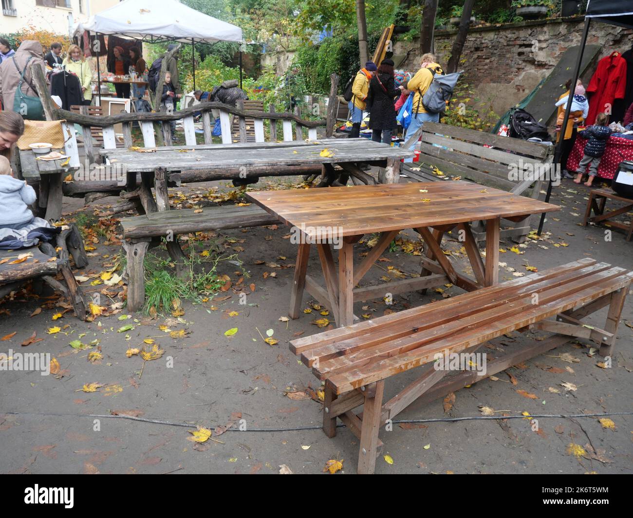 Flea market in a garden, many thing to sell, unrecognisable people and ...