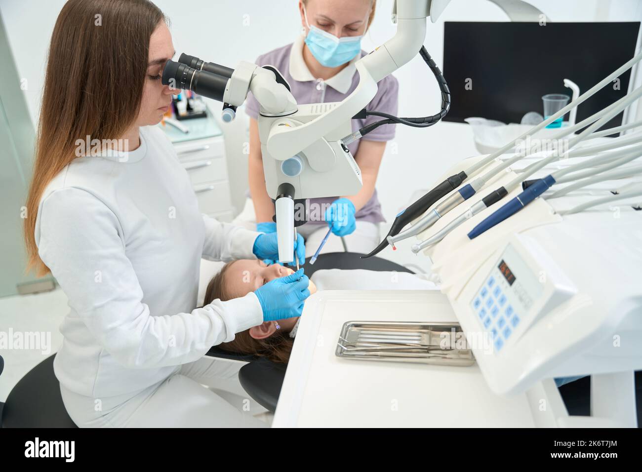 Dentist inspecting young patient oral cavity with modern diagnostic ...