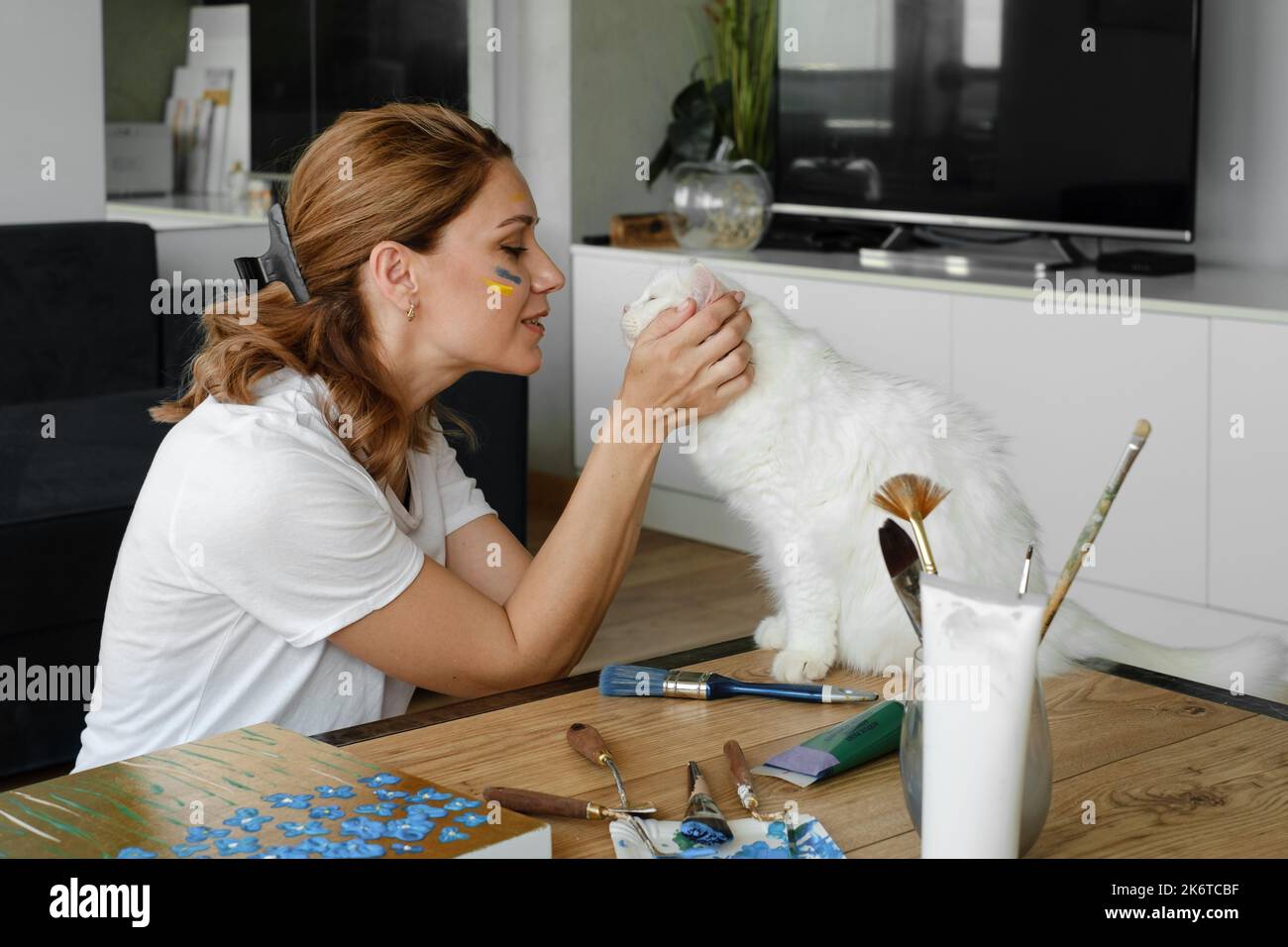 Woman artist painting picture at home with paints and cuddling with ...