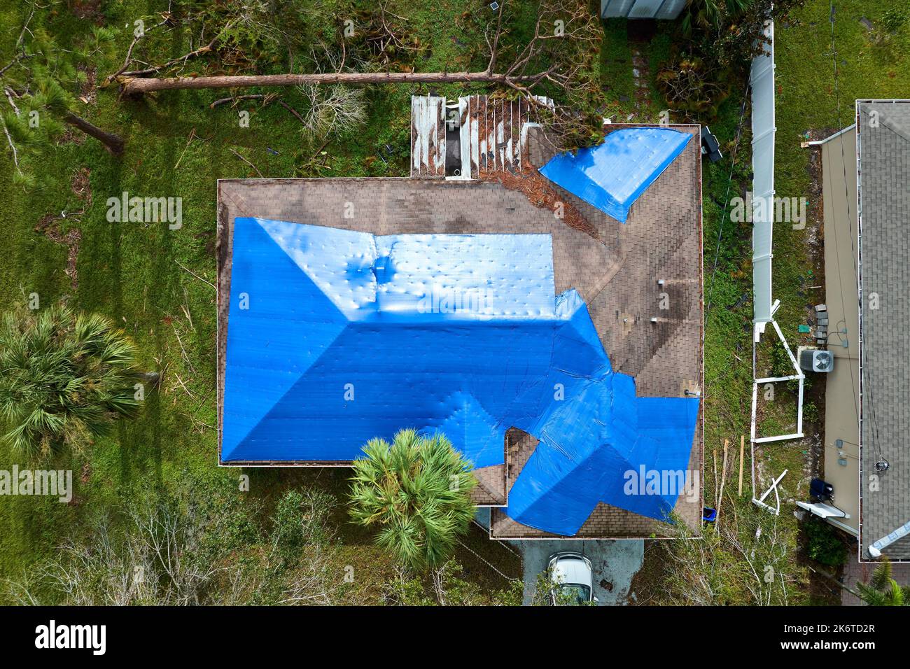 Aerial view of damaged in hurricane Ian house roof covered with blue ...