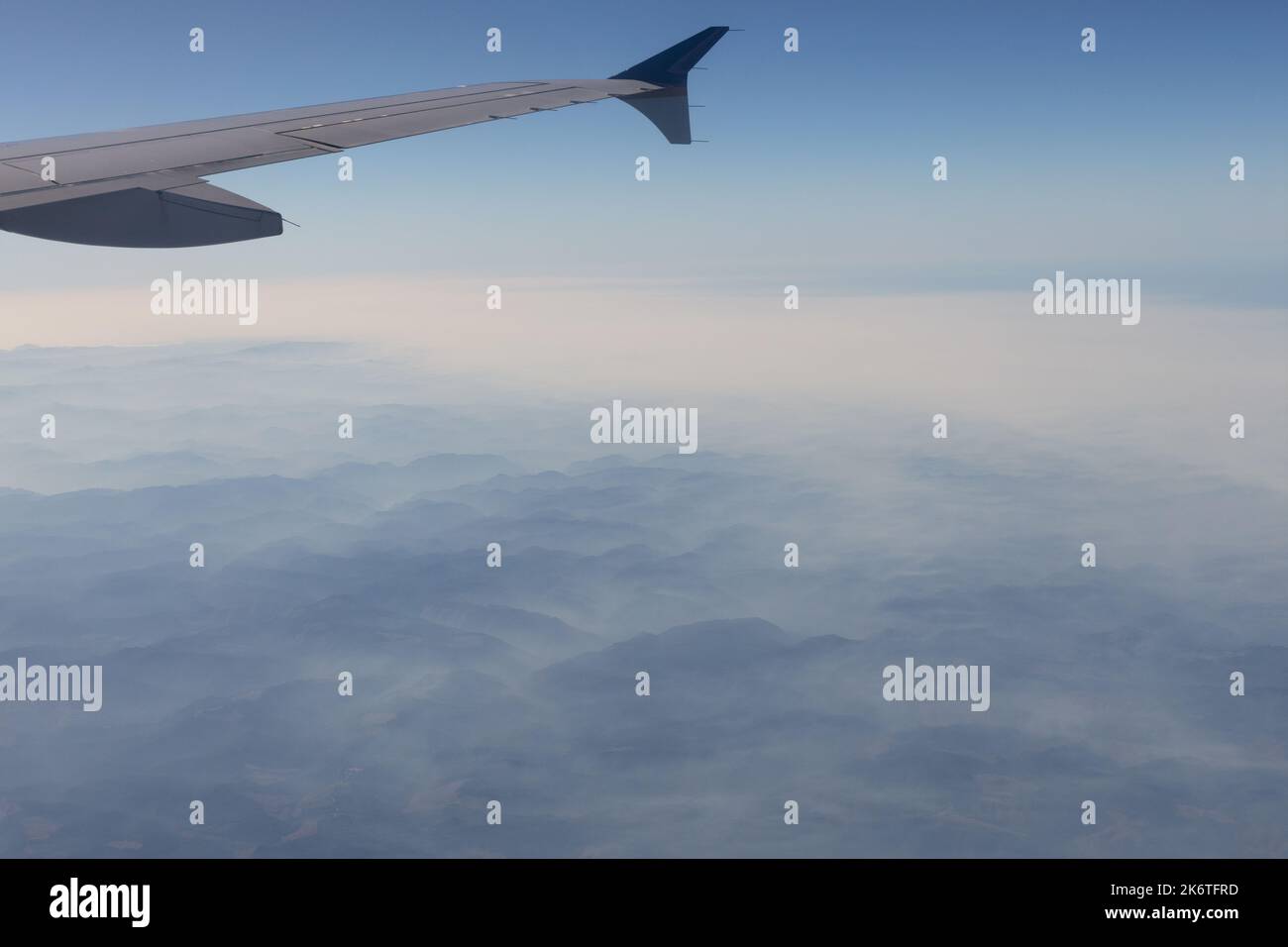 Passenger view from a commercial jet flying over smoke from wildfires ...