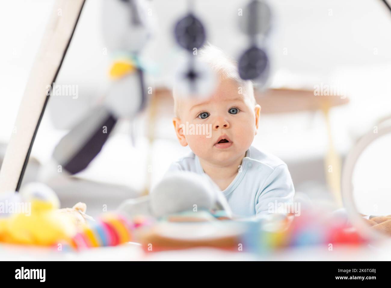 Cute baby boy playing with hanging toys arch on mat at home Baby ...