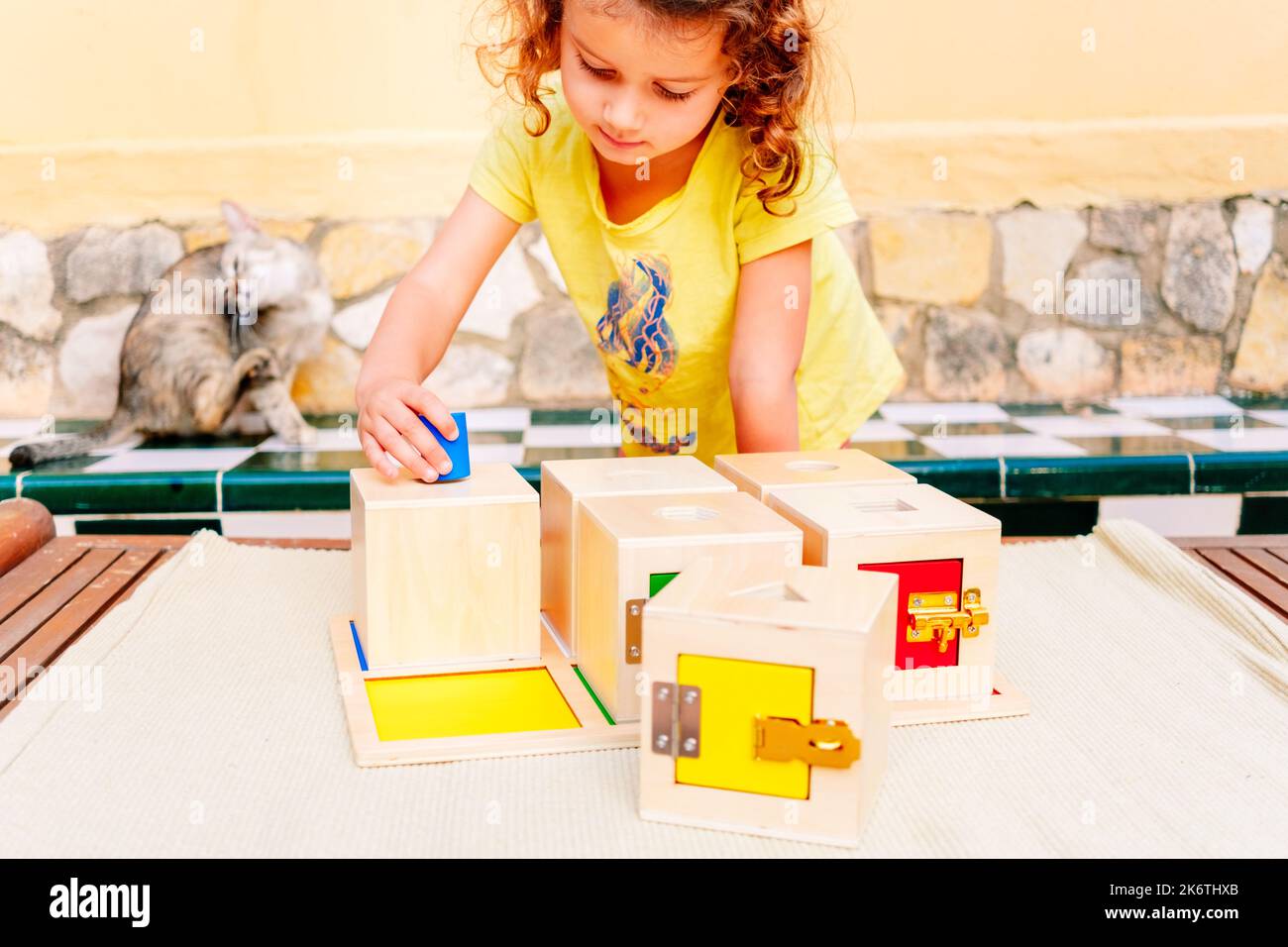 A girl manipulates sensory montessori material, wooden boxes to fit ...