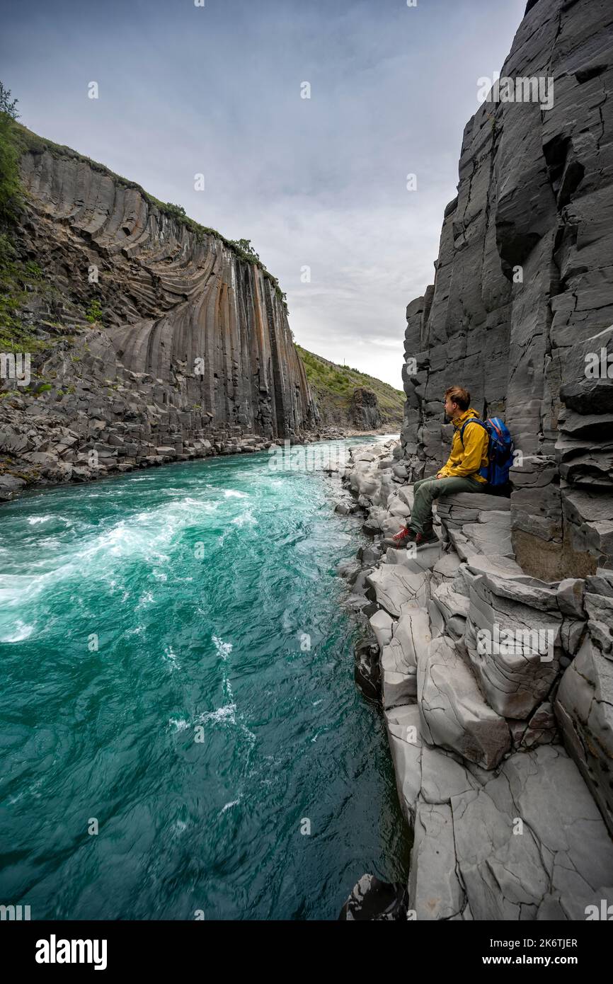 Tourist standing by the river in Stuolagil Canyon, turquoise blue river ...