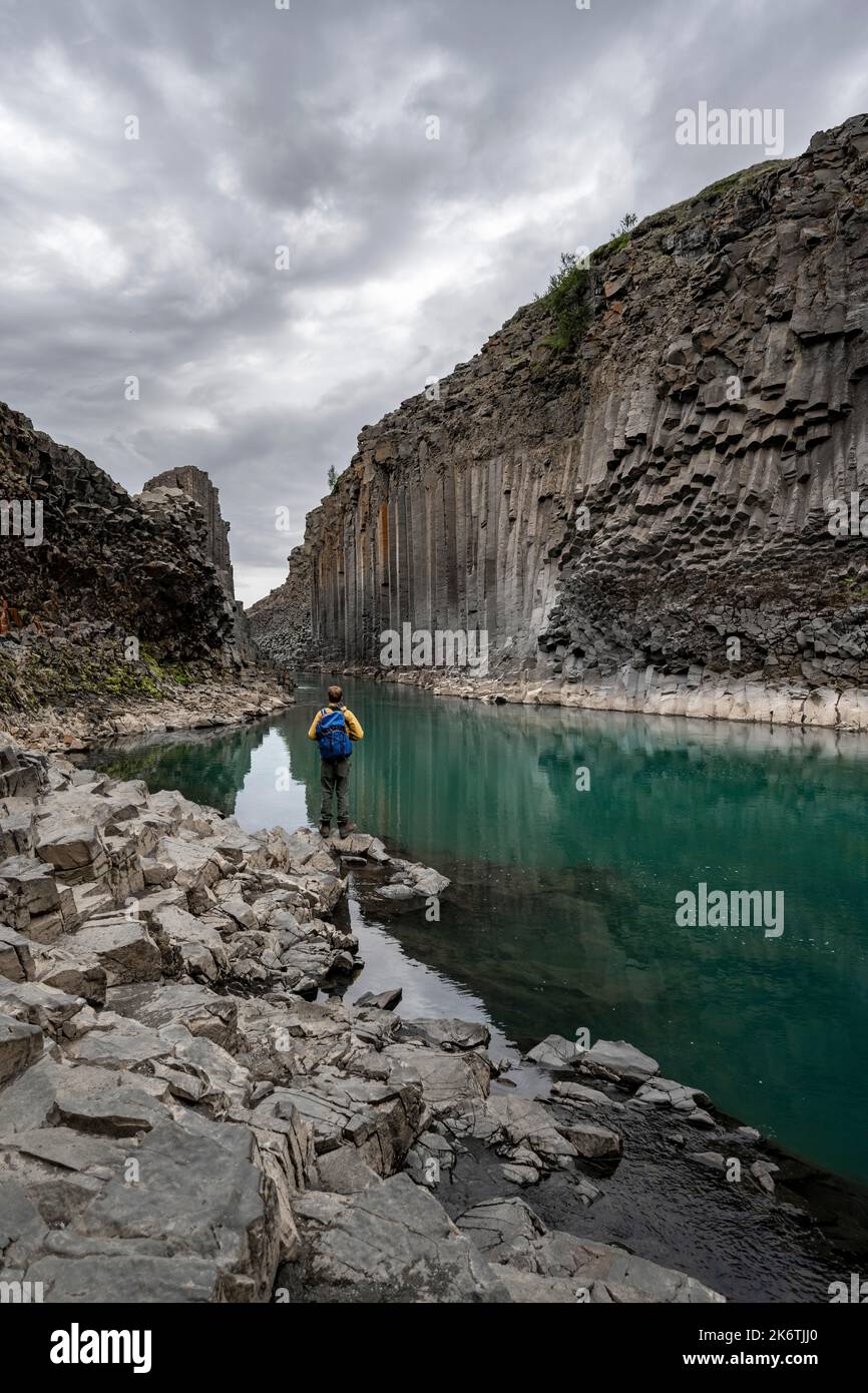 Tourist standing by the river in Stuolagil Canyon, turquoise blue river ...