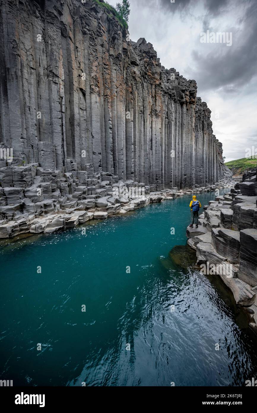 Tourist standing by the river in Stuolagil Canyon, turquoise blue river ...