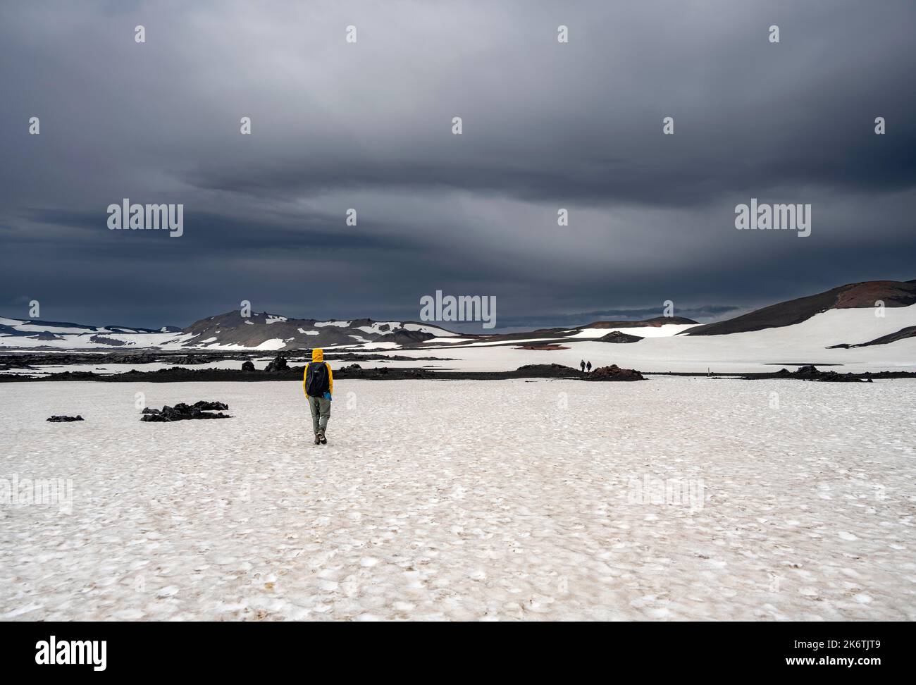 Hikers in snow-covered volcanic landscape with volcanic sand and ...