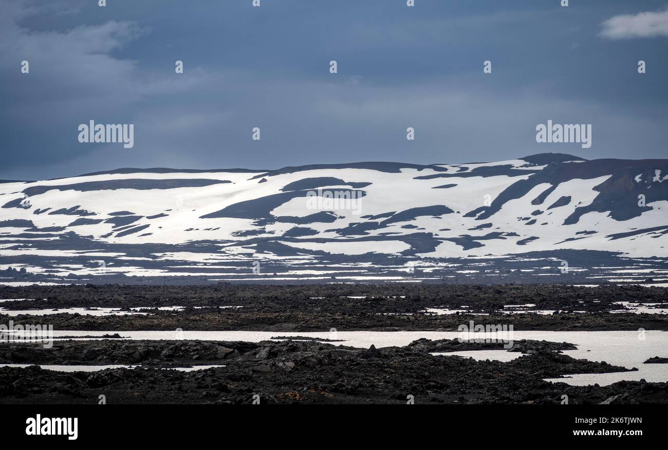 Snow-covered volcanic landscape with volcanic sand and petrified lava ...