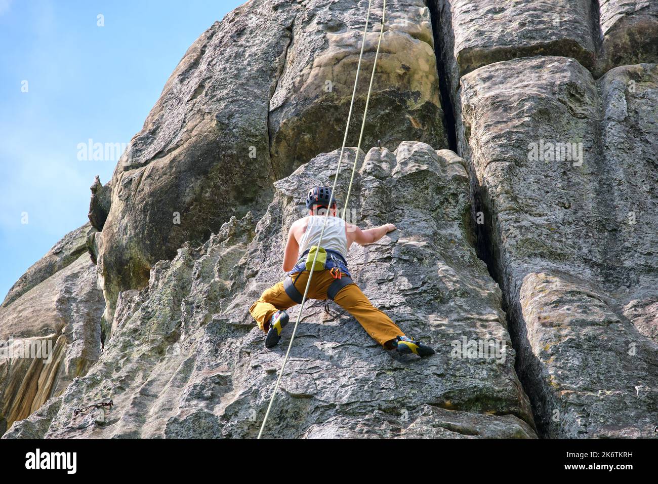 Determined climber clambering up steep wall of rocky mountain ...