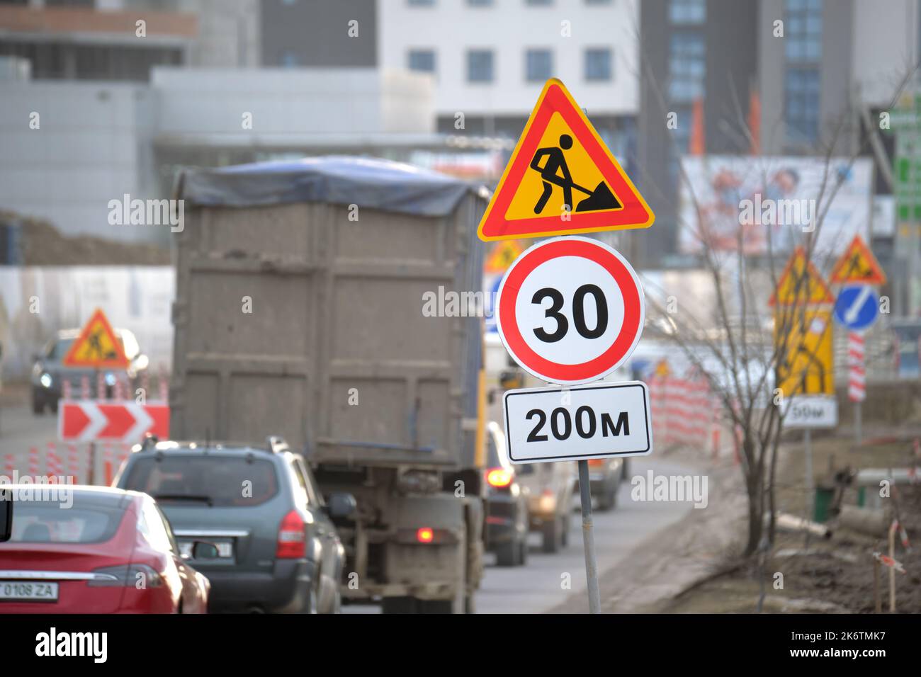 Roadworks warning traffic signs of construction work on city street and slowly moving cars Stock ...