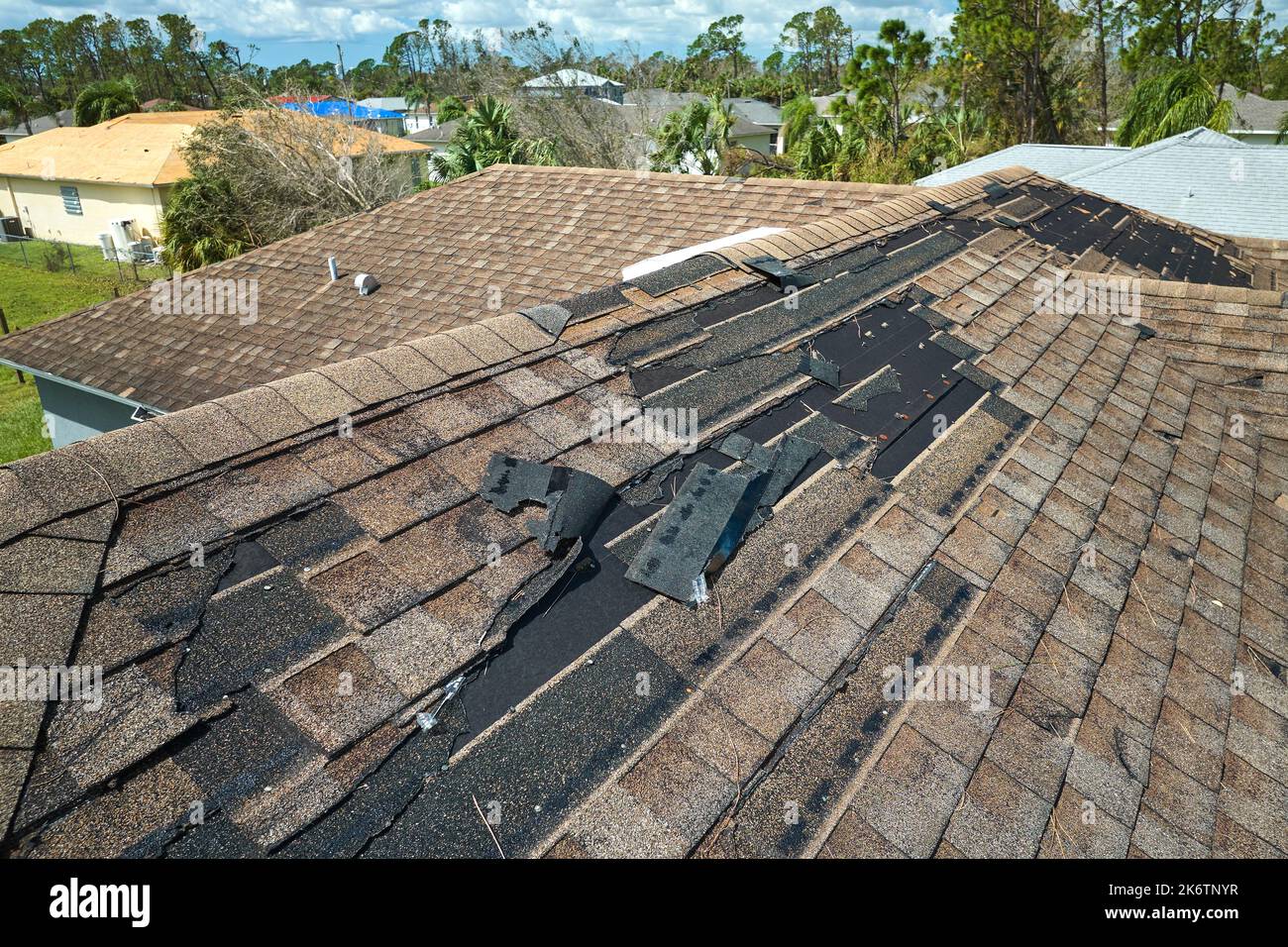 Wind damaged house roof with missing asphalt shingles after hurricane ...