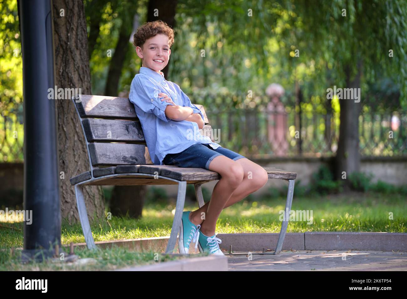 Young happy child boy relaxing sitting on bench in summer park ...