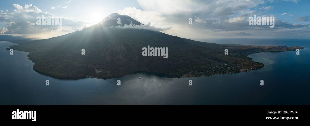 Evening sunlight peeks around the active volcano of Iliape in the ...