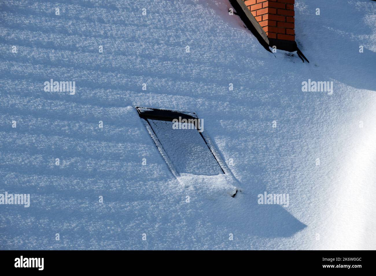Closeup of house roof top with attic windows covered with snow in cold ...