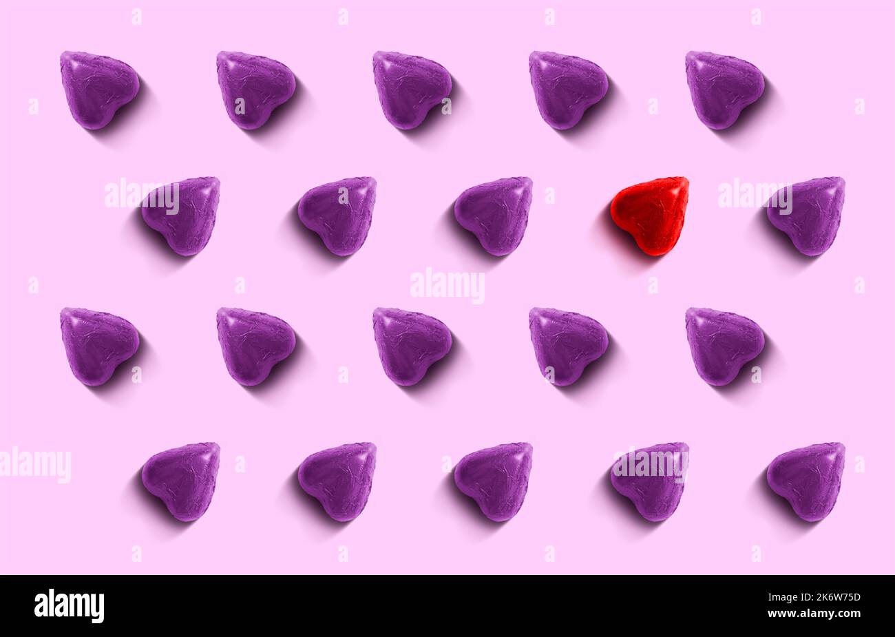 Pattern of heart shaped candies wrapped in foil with one red heart ...