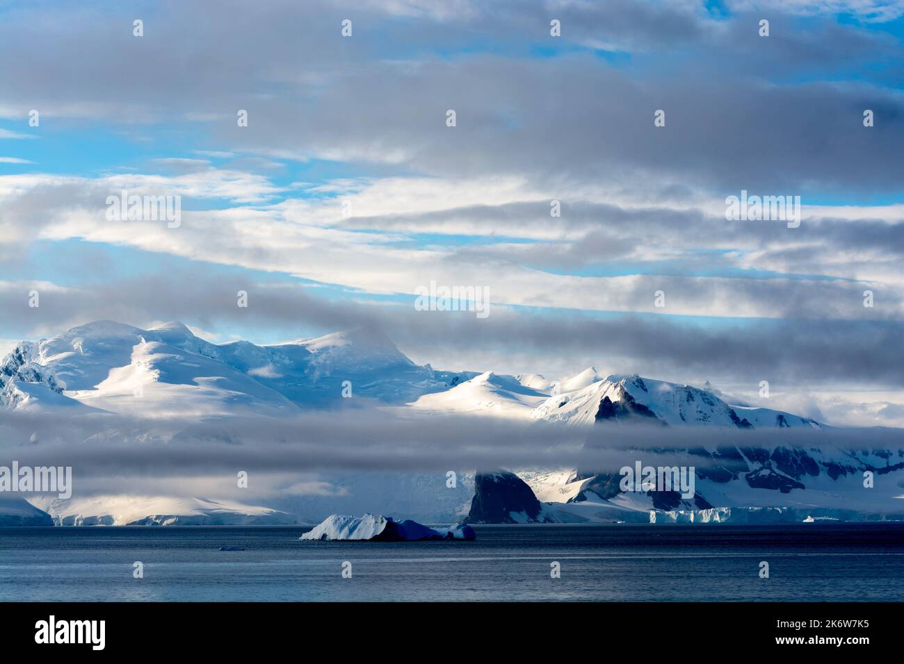 snow and cloud covered mountains of antarctic peninsula with dark rocks ...