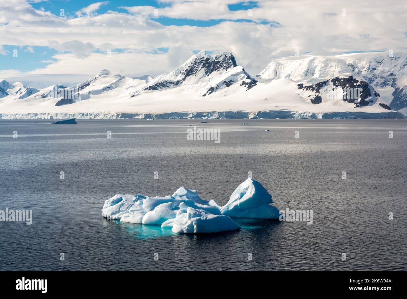 blue iceberg in front of bryde island and snow covered peaks of ...