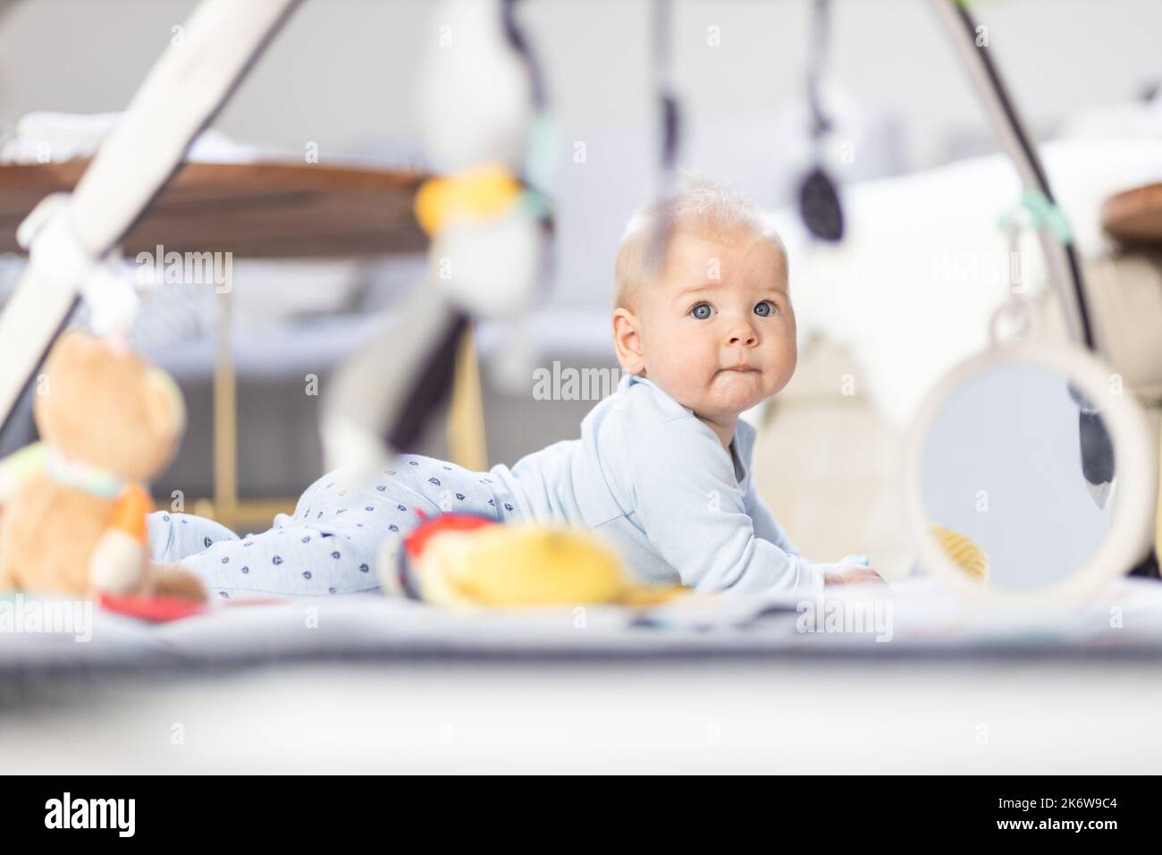 Cute baby boy playing with hanging toys arch on mat at home Baby ...