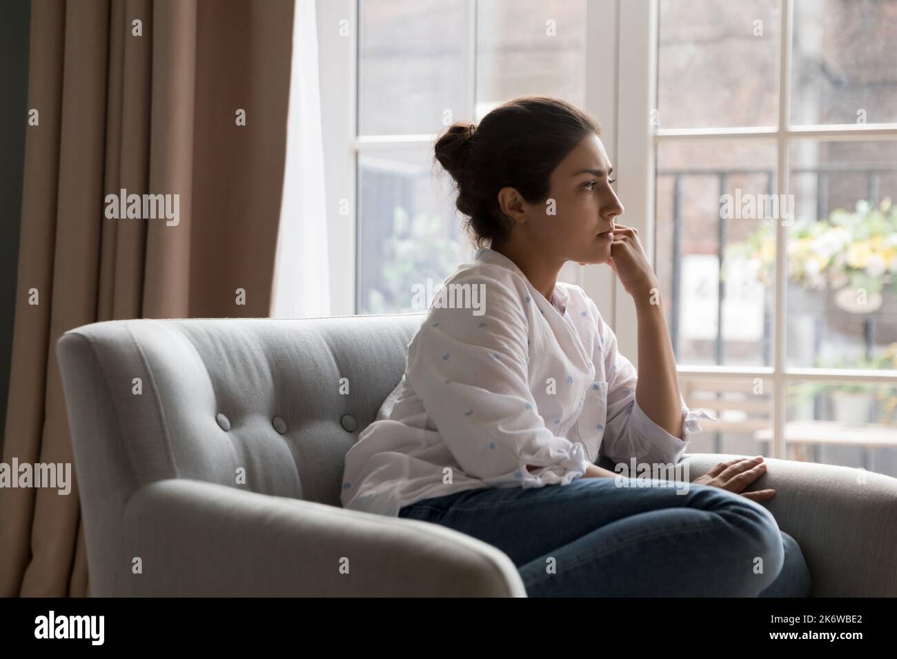 Sad Indian woman thinking sit on armchair and staring aside Stock Photo ...