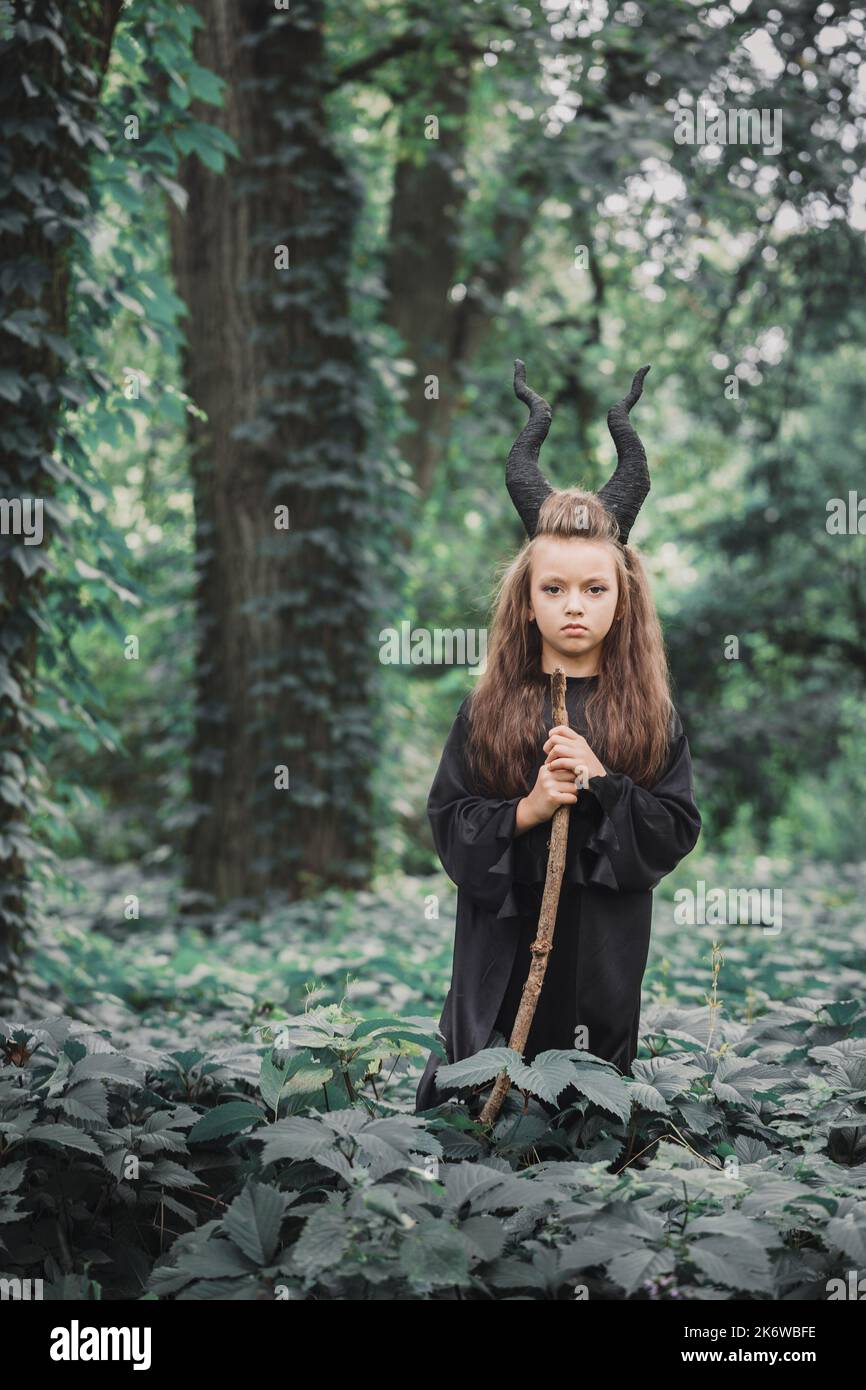 Little magical witch with big horns Maleficent in the forest. Halloween ...