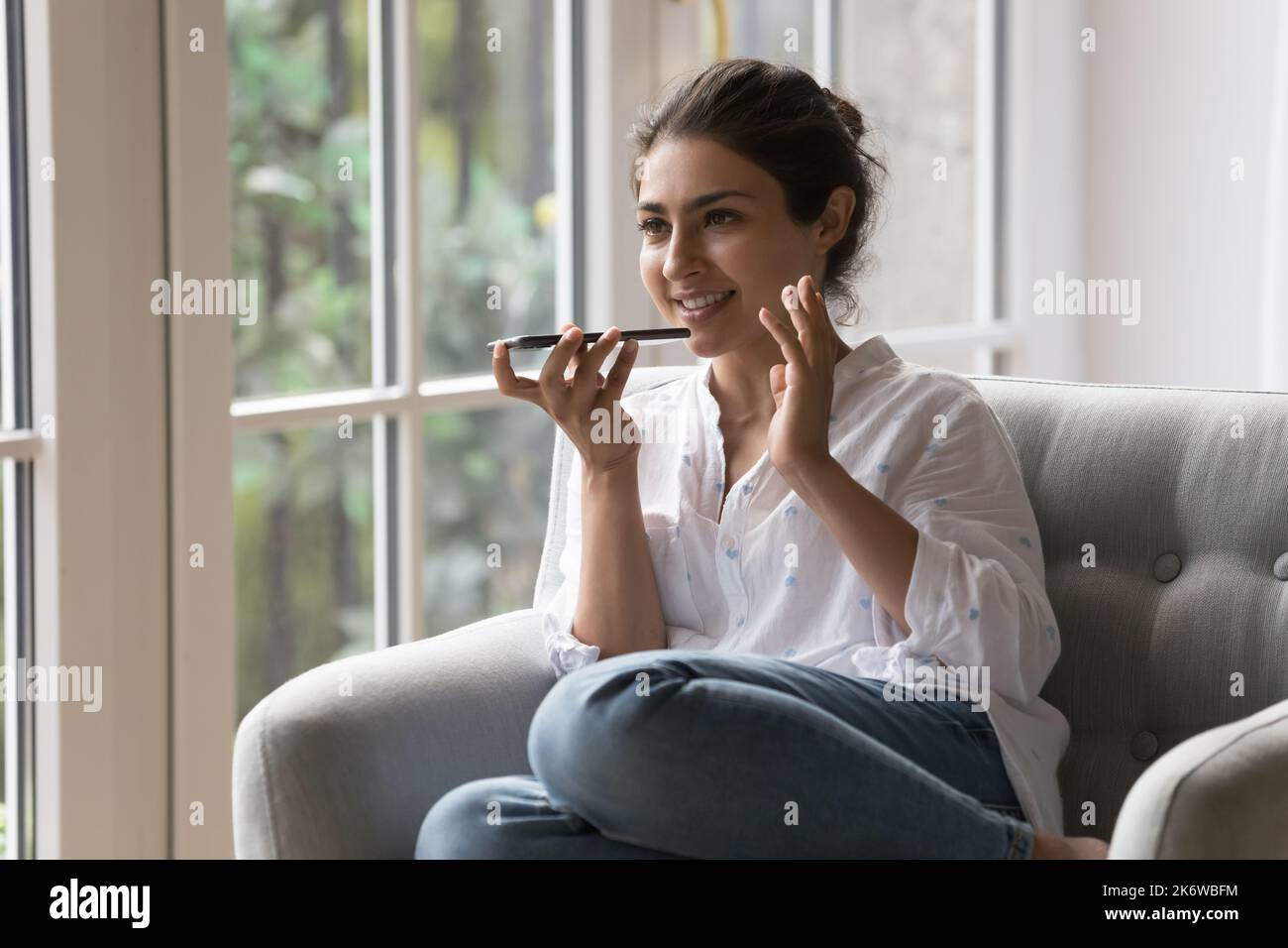 Smiling Indian woman holds smartphone talking on speakerphone Stock ...