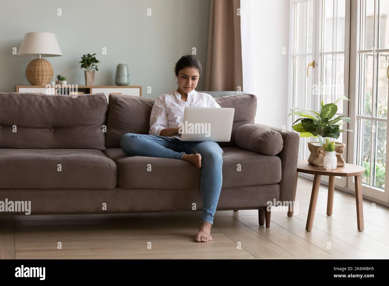 Serious Indian woman use laptop texting e-mail seated on couch Stock ...