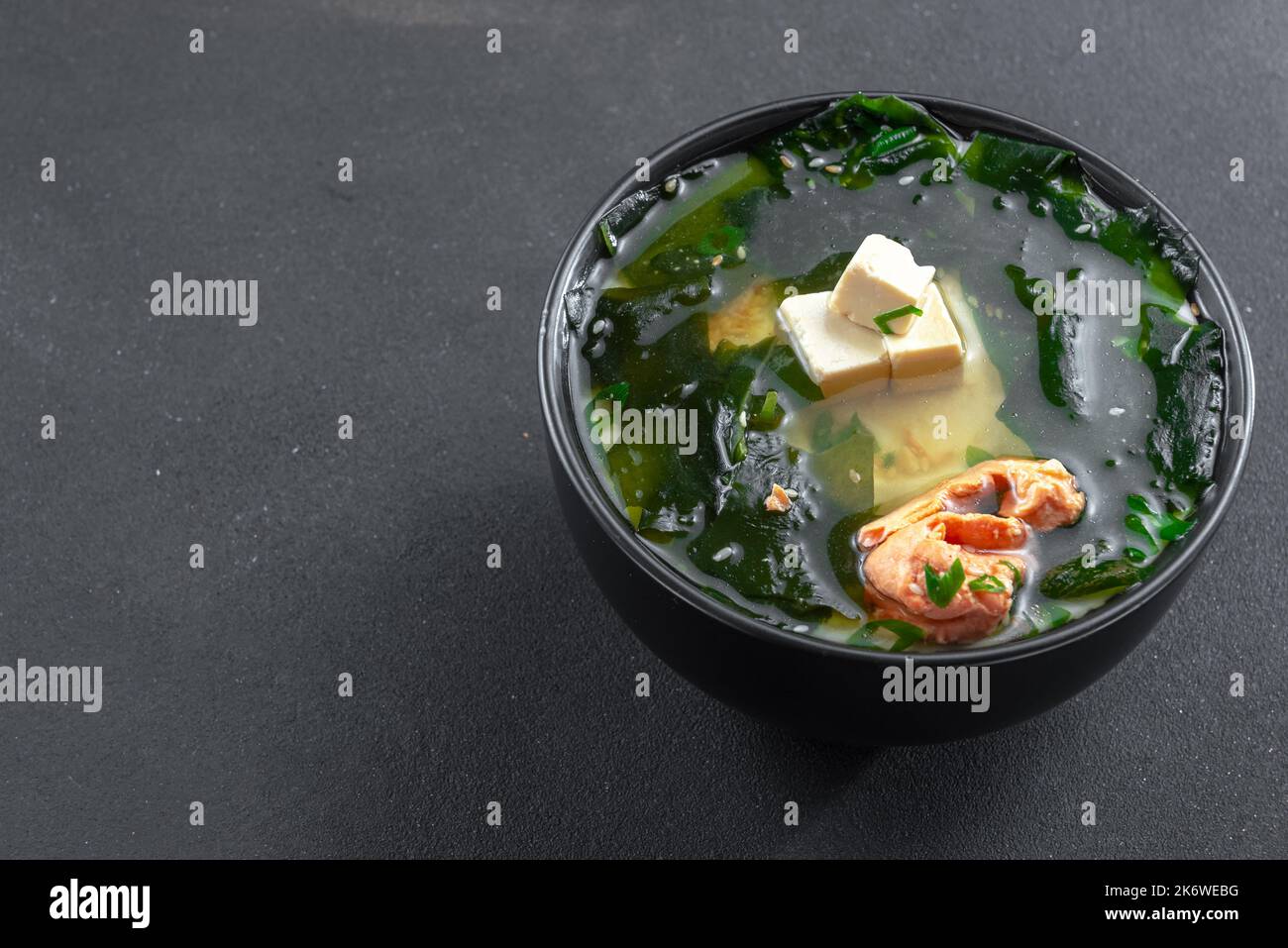 Muso soup with salmon in a black bowl on a black background. Asian food ...