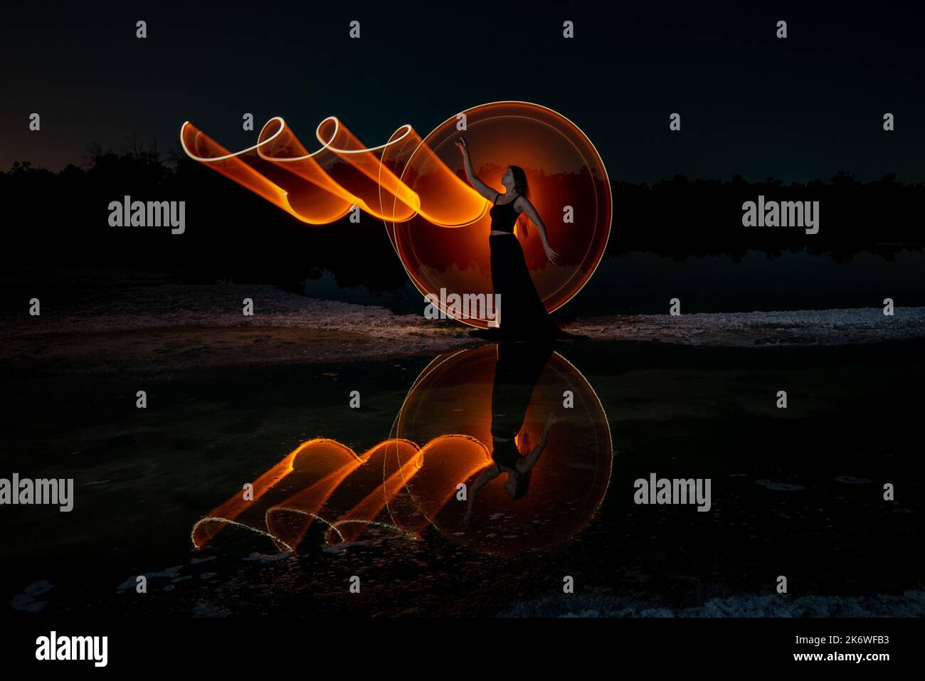 Woman posing for lightpainting photos with bright lights in the dark ...