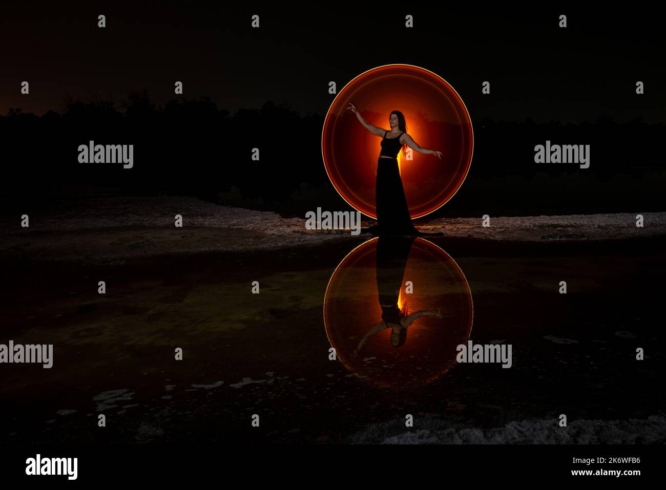 Woman posing for lightpainting photos with bright lights in the dark ...