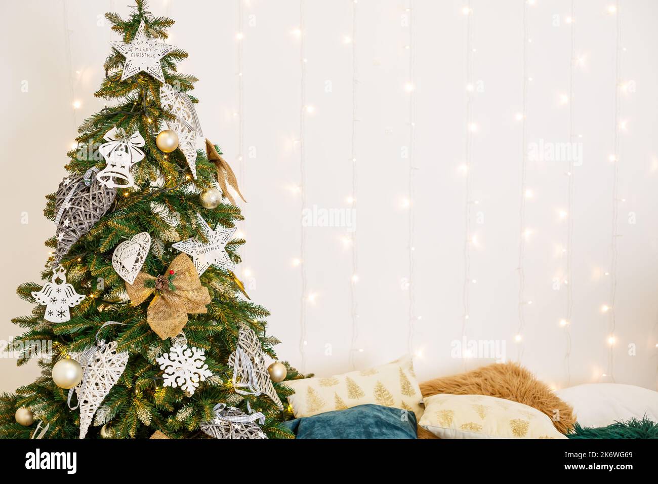 A cozy room decorated with garlands and Christmas trees. White pillow ...