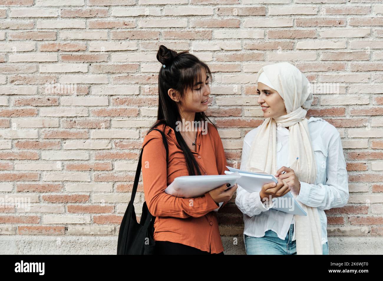 Multi-ethnic female friends talking and sharing ideas while studying ...