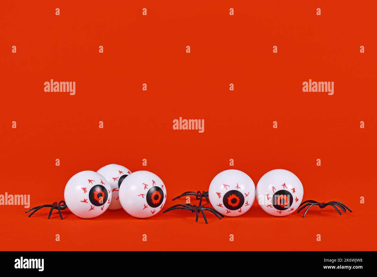 Spooky Halloween eyeballs and spiders on red background with copy space ...