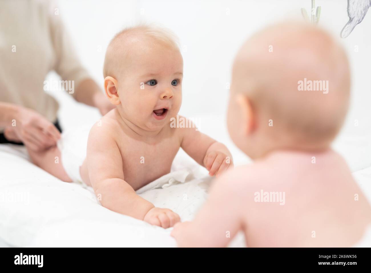 Beautiful shot of a cute baby boy looking at his reflection in big ...