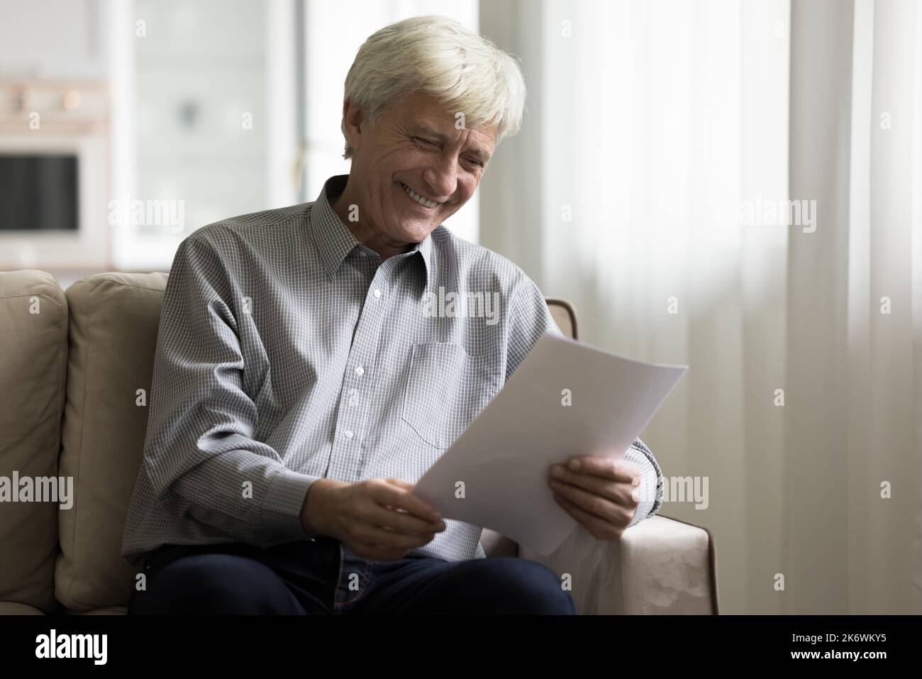 Grey-haired senior man smiles while read paper letter Stock Photo - Alamy
