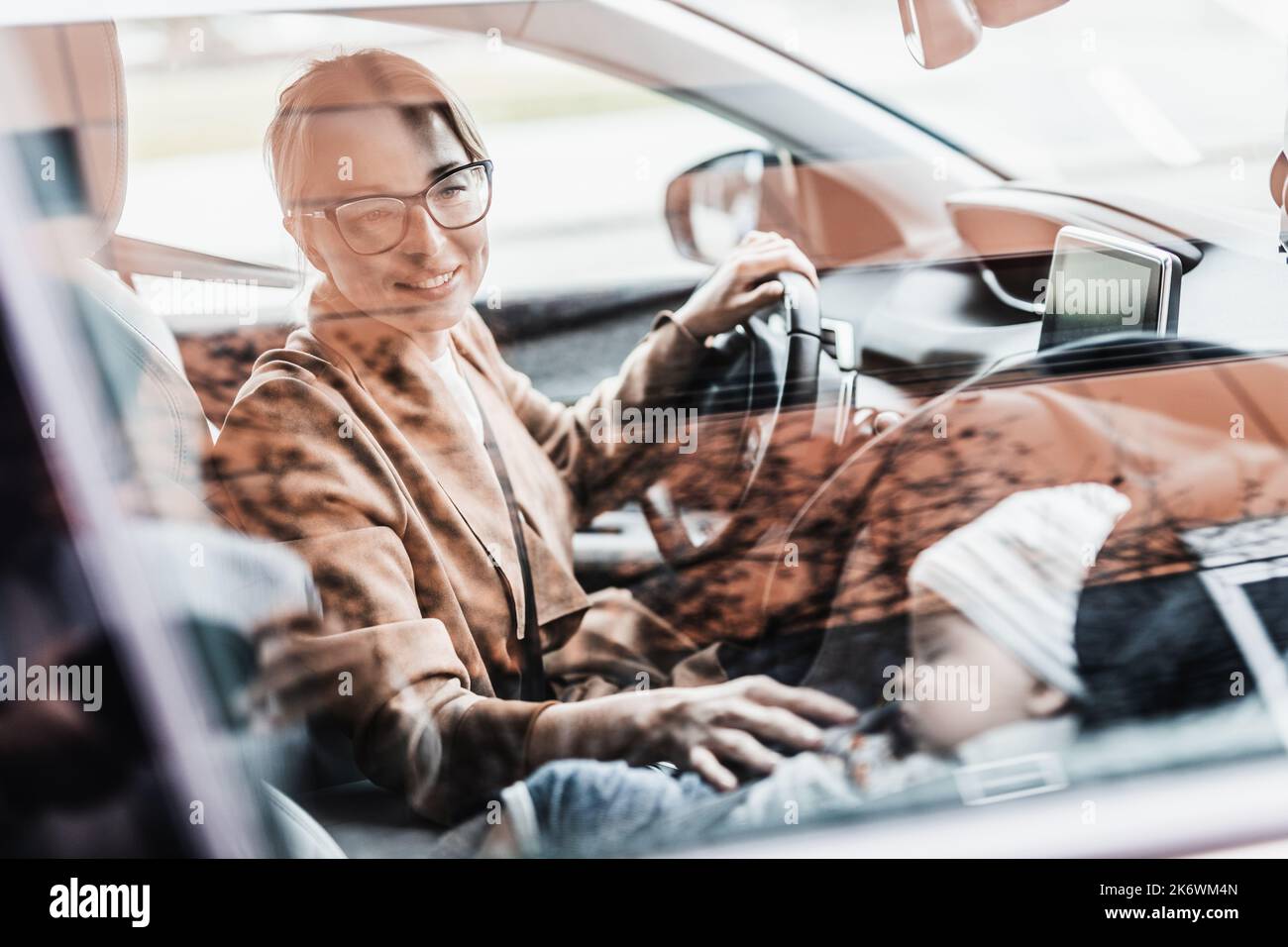 Mother driving family car, running errands, while her baby sleeps in ...