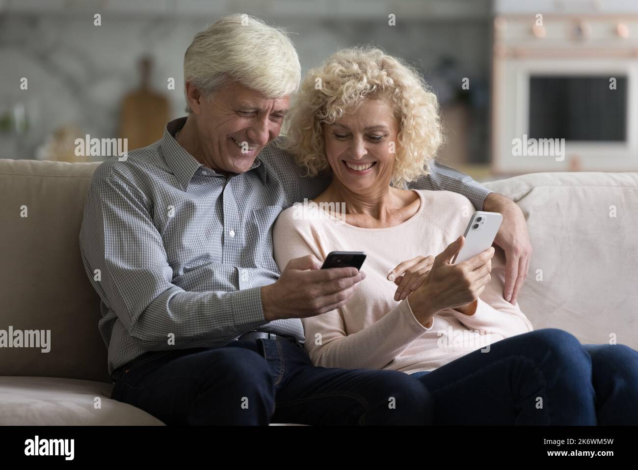 Positive mature spouses spend time using two modern smartphones Stock ...